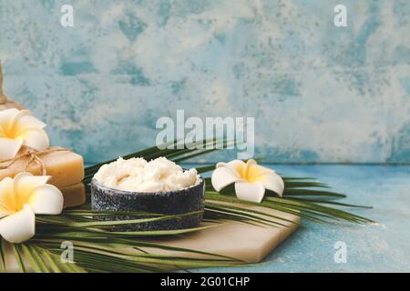 Bowl with shea butter, soap and palm leaves on color background ...