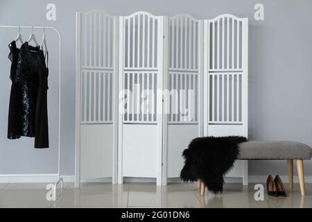 Modern ottoman and folding screen near light wall Stock Photo - Alamy