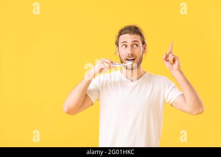 Young man pointing at toothbrush on color background Stock Photo - Alamy