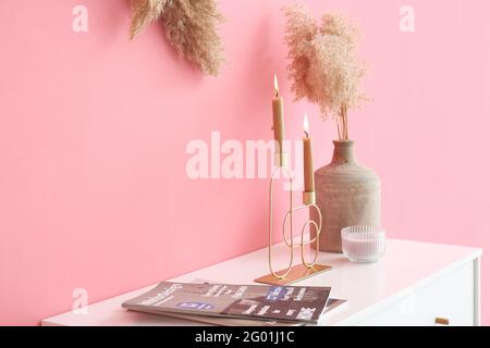 Chest of drawers with candles and vase near color wall Stock Photo - Alamy