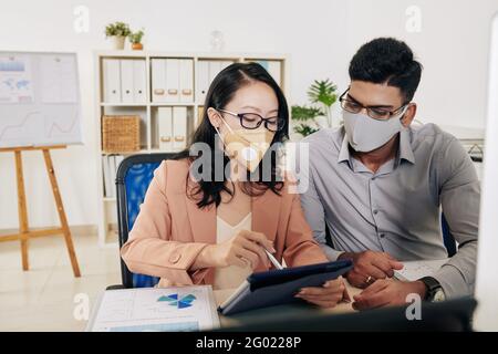 business colleagues in protective masks sitting at the office Desk ...