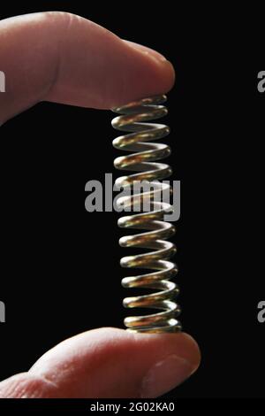 The male hand squeezes a metal spring on a white background Stock Photo ...