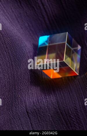 Glass cube with color spectrum rays on fabric. Abstract background with ...