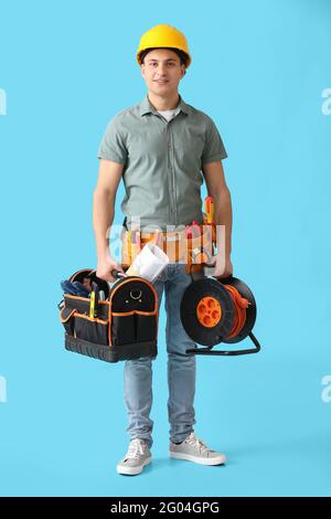 Young electrician with tools on color background Stock Photo - Alamy