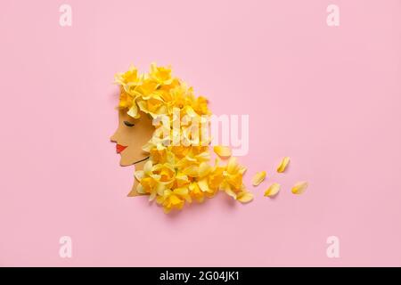 Paper female figure with beautiful daffodils on color wooden background ...