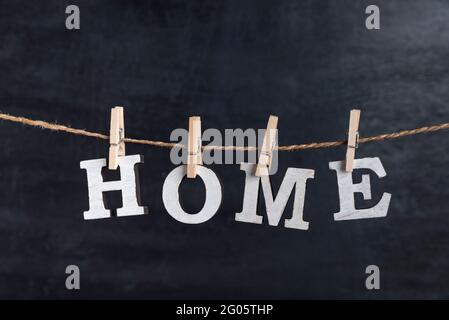 Word HOME with clothespins on black background. White wooden letters ...
