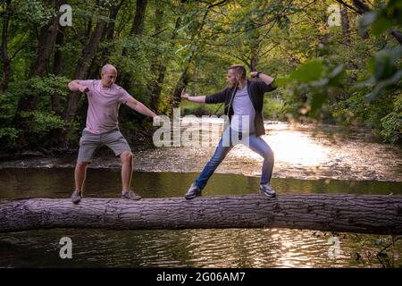 Two guys play fighting in martial arts style on a log bridge Stock ...