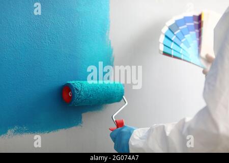 Master painter holds in his hands color palette with shades of blue ...