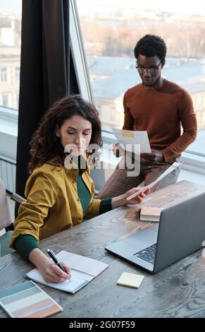 Two young men working at the computer in coworking office. Seen through ...