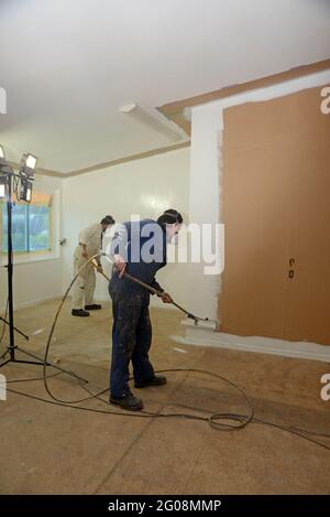 a tradesman using airless spray equipment to paint a primer coat on the ...
