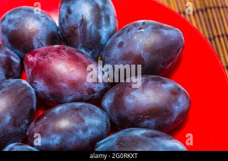 Large fresh purple plum fruits with a woven napkin on a bamboo mat ...
