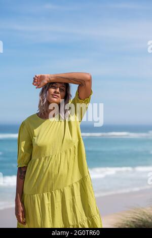 Woman covering her face from sun with her hand while standing against ...