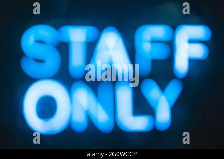 Neon letters, bright signboard staff only on a black wall close-up ...