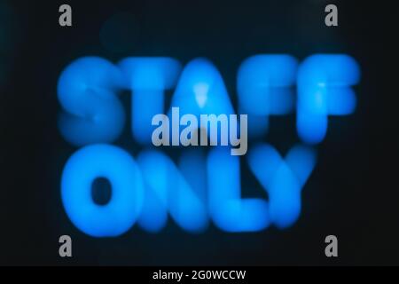 Neon letters, bright signboard staff only on a black wall close-up ...