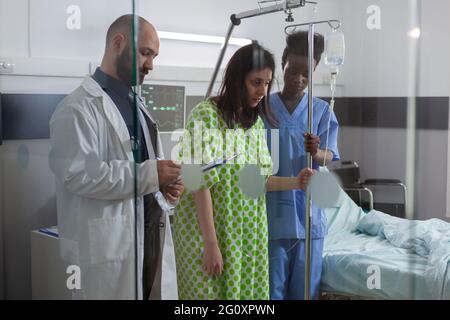 Black asisstant with practitioner doctor helping patient to stand up ...