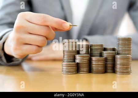 Businesswoman put coins to stack of coins Stock Photo - Alamy