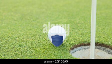 Composition of golf ball with face mask on grass with copy space Stock ...