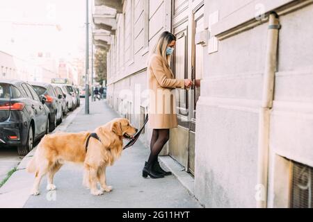 Woman with dog entering apartment building Stock Photo - Alamy