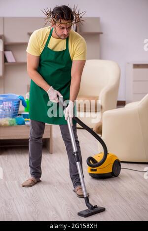 Young male contractor wearing prickly wreath on head doing housework ...