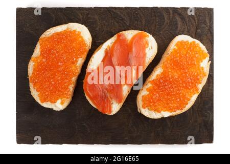 Open-face sandwiches with salmon roe on wooden serving board, isolated ...