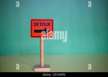 Closeup shot of a red "Detour" sign with a black arrow indicating ...