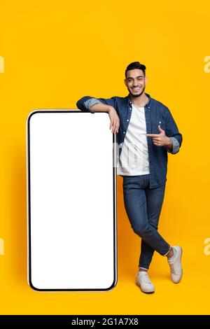 Cool mobile app. Millennial arab spouses standing near giant smartphone ...