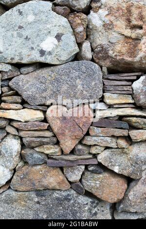 A heart-shaped stone stuck in the middle of a wall with other small and ...