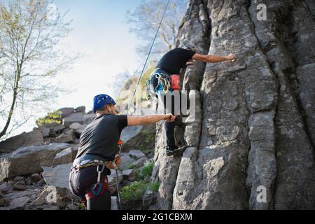 Senior man with instructor climbing rocks outdoors in nature, active ...