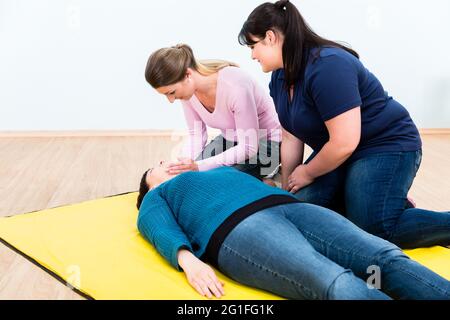 Women in first aid class training to position injured person Stock ...