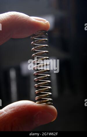 The male hand squeezes a metal spring on a black background Stock Photo ...