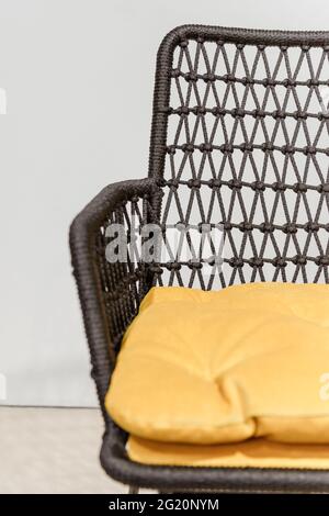 Black wicker chair with yellow pillows. Details Stock Photo - Alamy