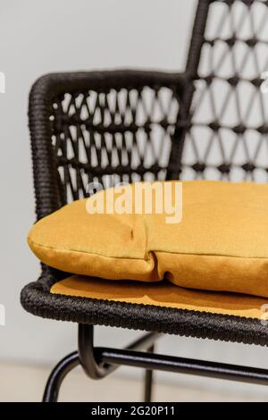 Black wicker chair with yellow pillows. Details Stock Photo - Alamy