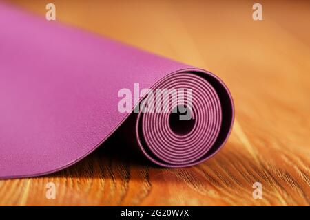 An unfolded lilac-colored yoga mat is unfolded on the wooden floor. Top ...