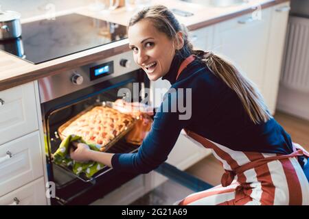 Woman removing pie from oven Stock Photo - Alamy