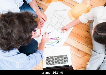 Architects or civil engineers bent over construction plans on the ...