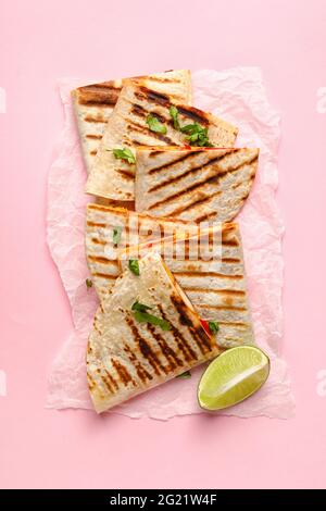 Parchment with tasty quesadillas and lime on color background Stock ...