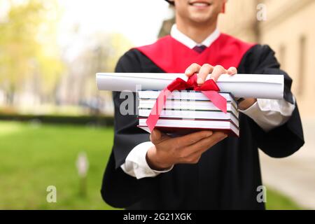 Male graduating student with books outdoors Stock Photo - Alamy