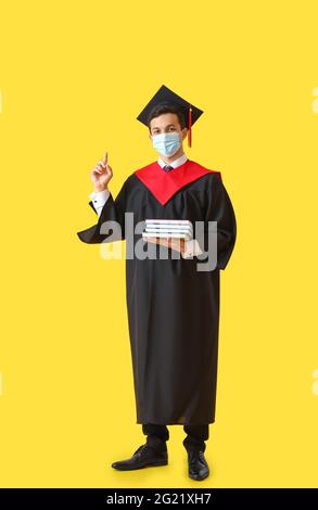 Male graduating student wearing medical mask on color background Stock ...