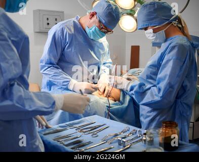 Surgical team doing aesthetic surgery in operating room. Doctors doing ...