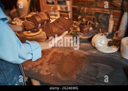 Unrecognized female arms making earthenware tableware in pottery ...