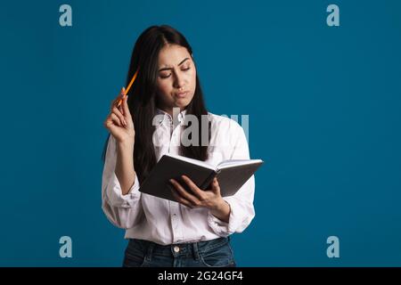 Brooding beautiful asian girl writing down notes in planner isolated ...