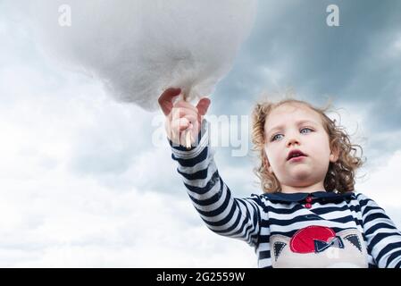 Portrait of a girl holding candy floss that looks like a cloud, Poland ...