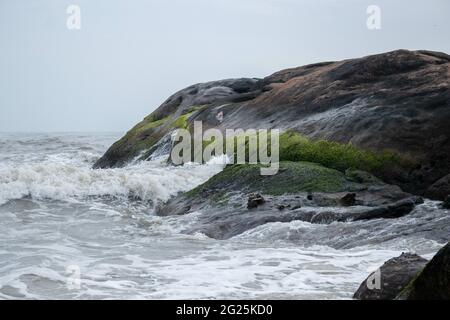 Foamy waves of the ocean hitting mossy rocks Stock Photo - Alamy
