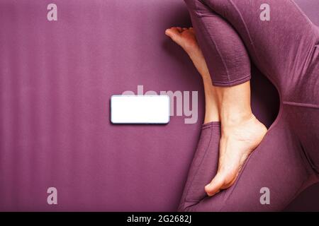 Online yoga practice. Mature asian man doing butterfly asana on sports ...