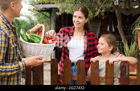 Good neighbors communicate while standing by fence between houses Stock ...