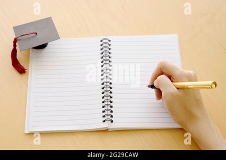 Blank notebook on the table and graduation cap Stock Photo - Alamy