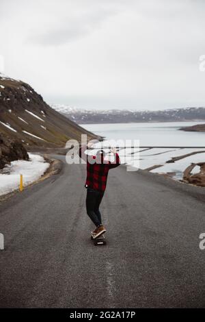 Hipster riding skateboard on remote road Stock Photo - Alamy