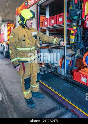 Professional fireman getting ready near fire truck and looking away ...