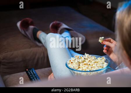 Close up of hand waking popcorn from a bowl while watching TV. Person ...
