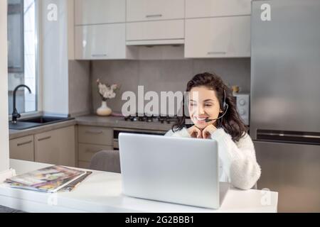 An operator in earphones sitting at the laptop while working from home ...